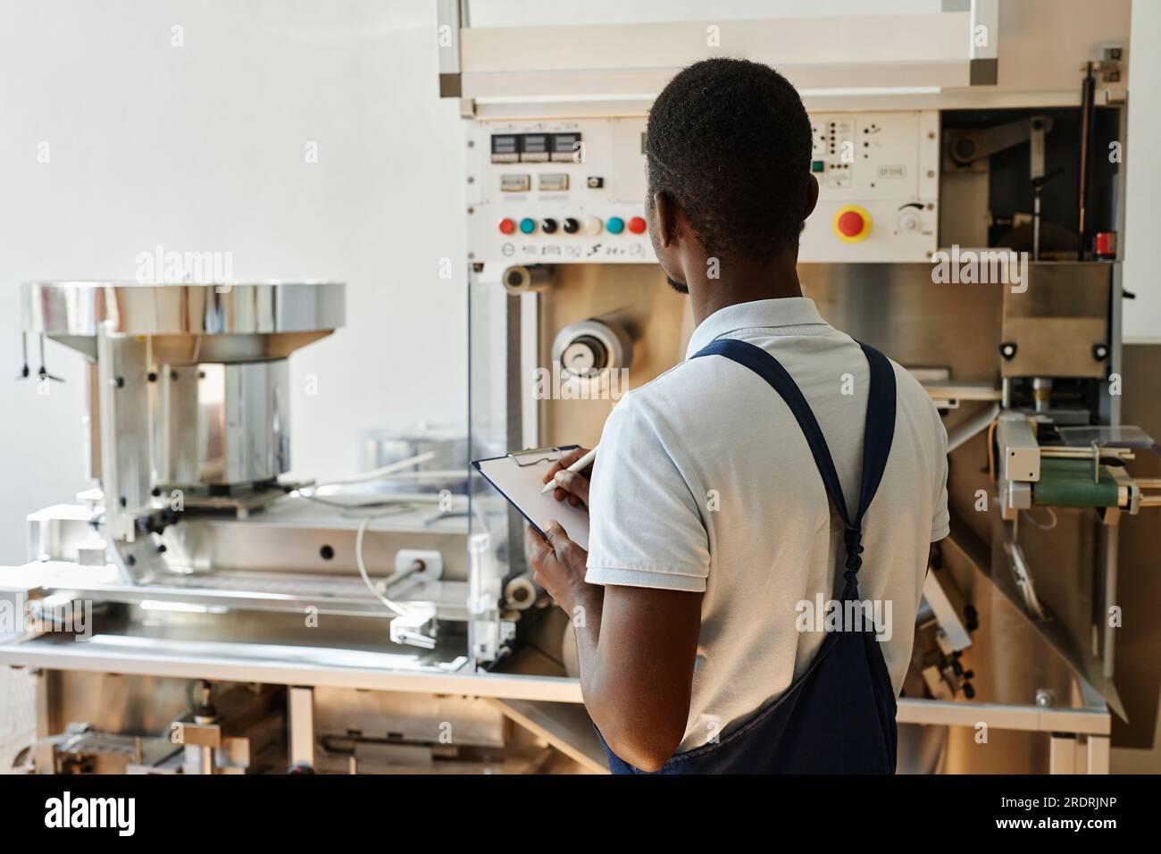 Back view of African American factory worker holding clipboard while ...