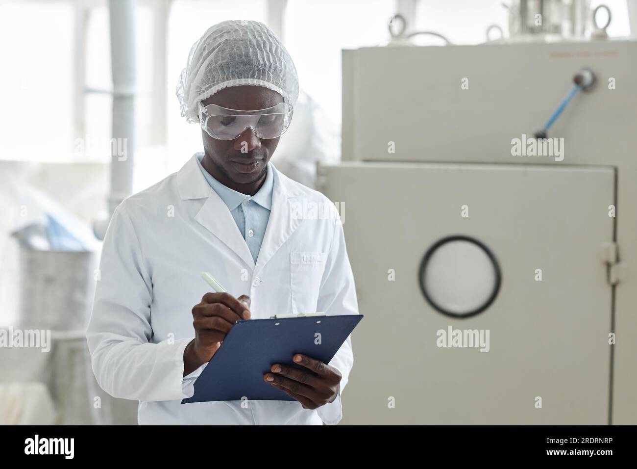 Waist up portrait of black young man wearing lab coat and writing on ...