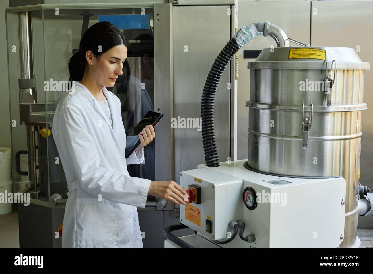 Side view portrait of adult woman wearing lab coat using machine unit ...