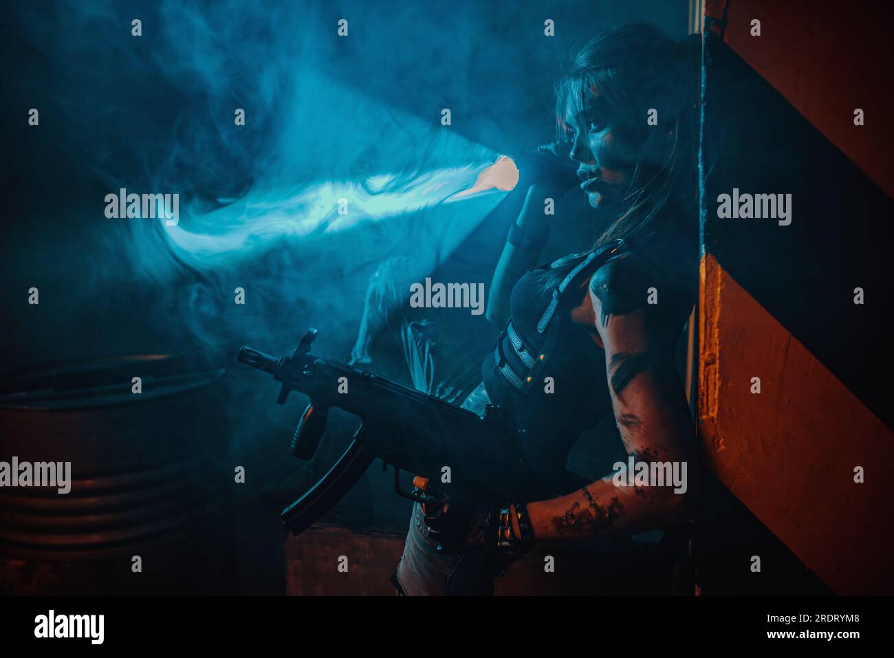 Young woman fighter with gun and flashlight in dramatic industrial ...