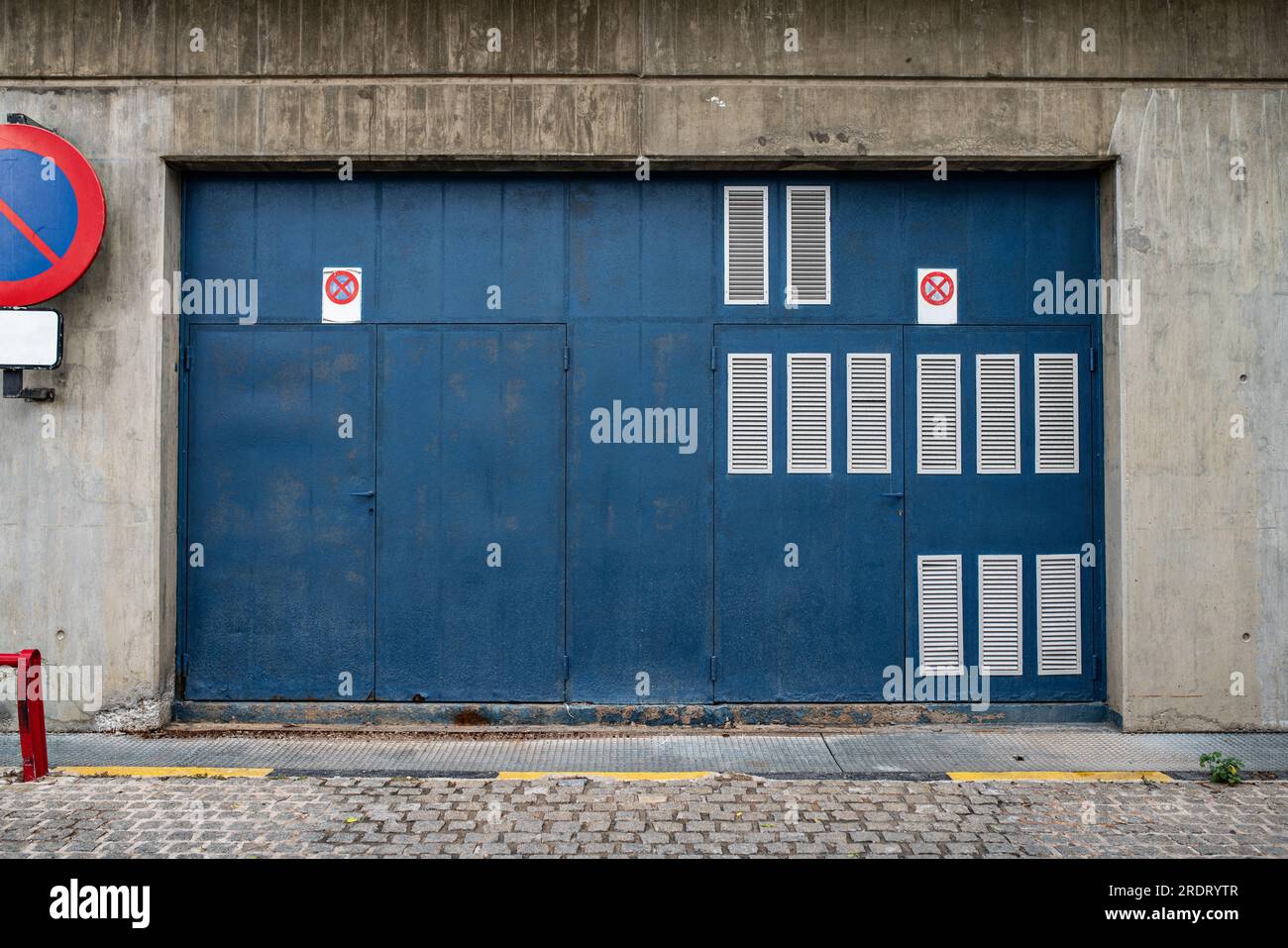 Urban street with blue gates and concrete wall Stock Photo - Alamy