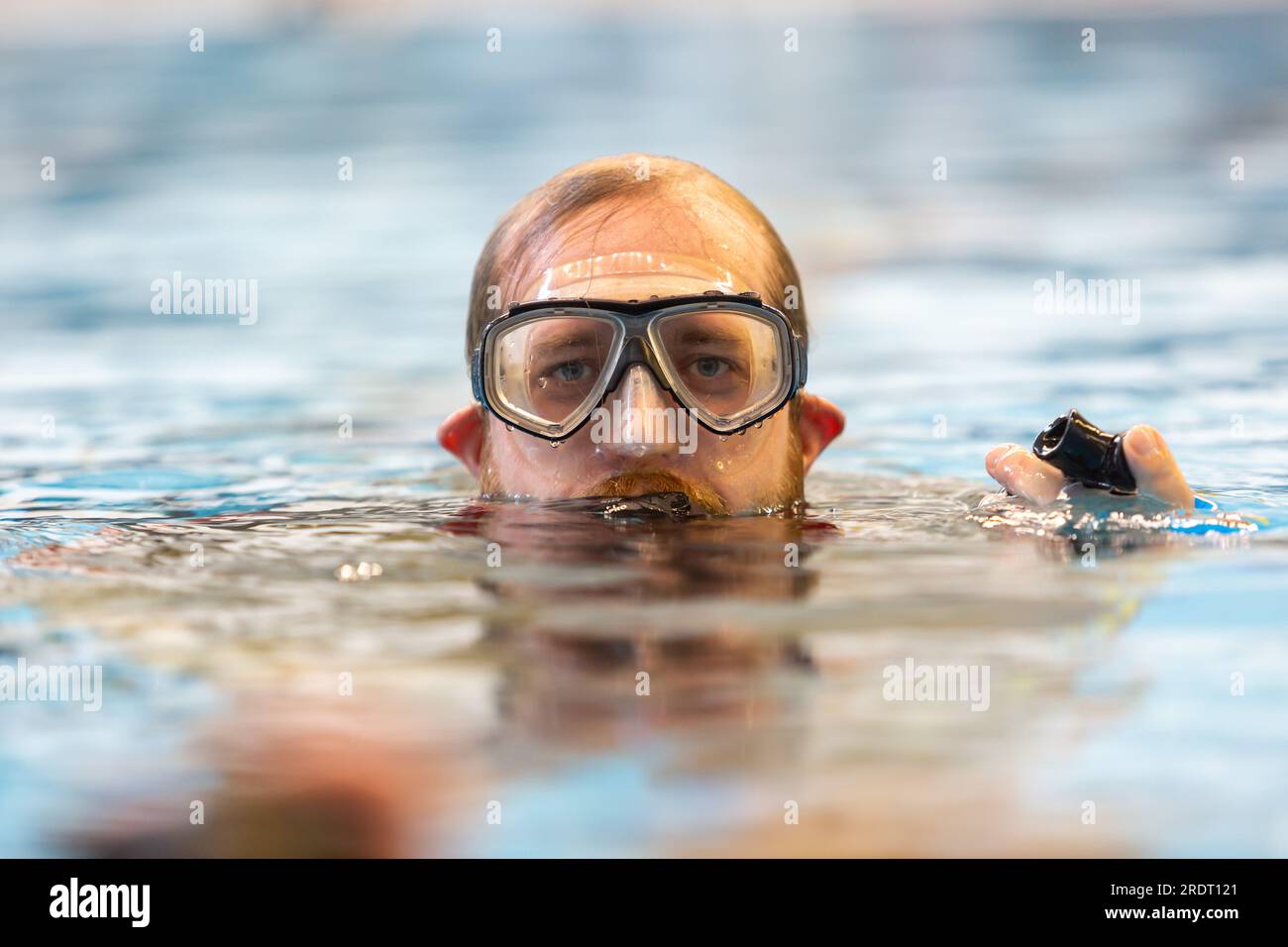 Sub-aqua diver wearing goggles at the water surface in an indoor ...