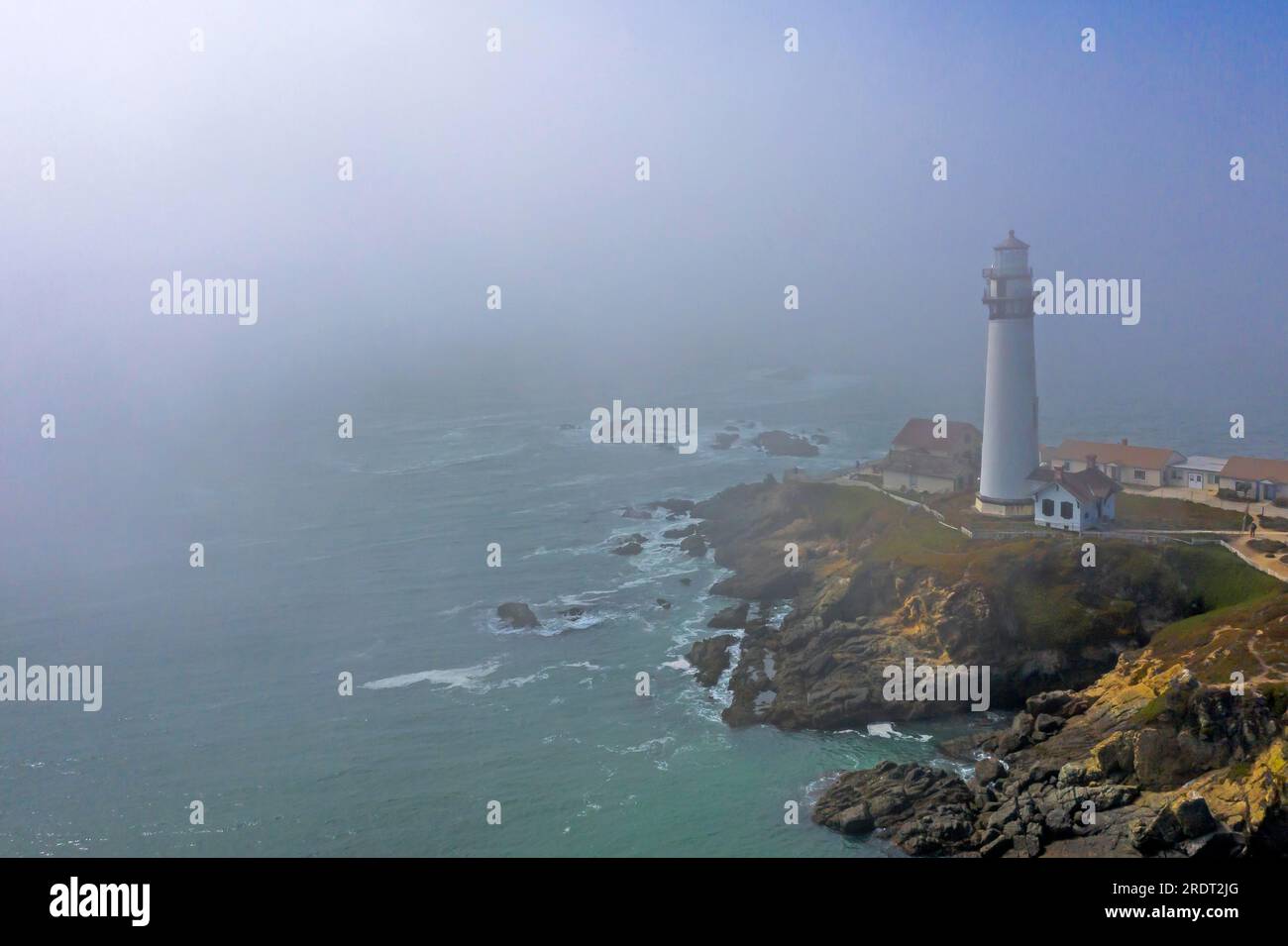 Aerial view of a lighthouse off the California Coast as fog settles in ...