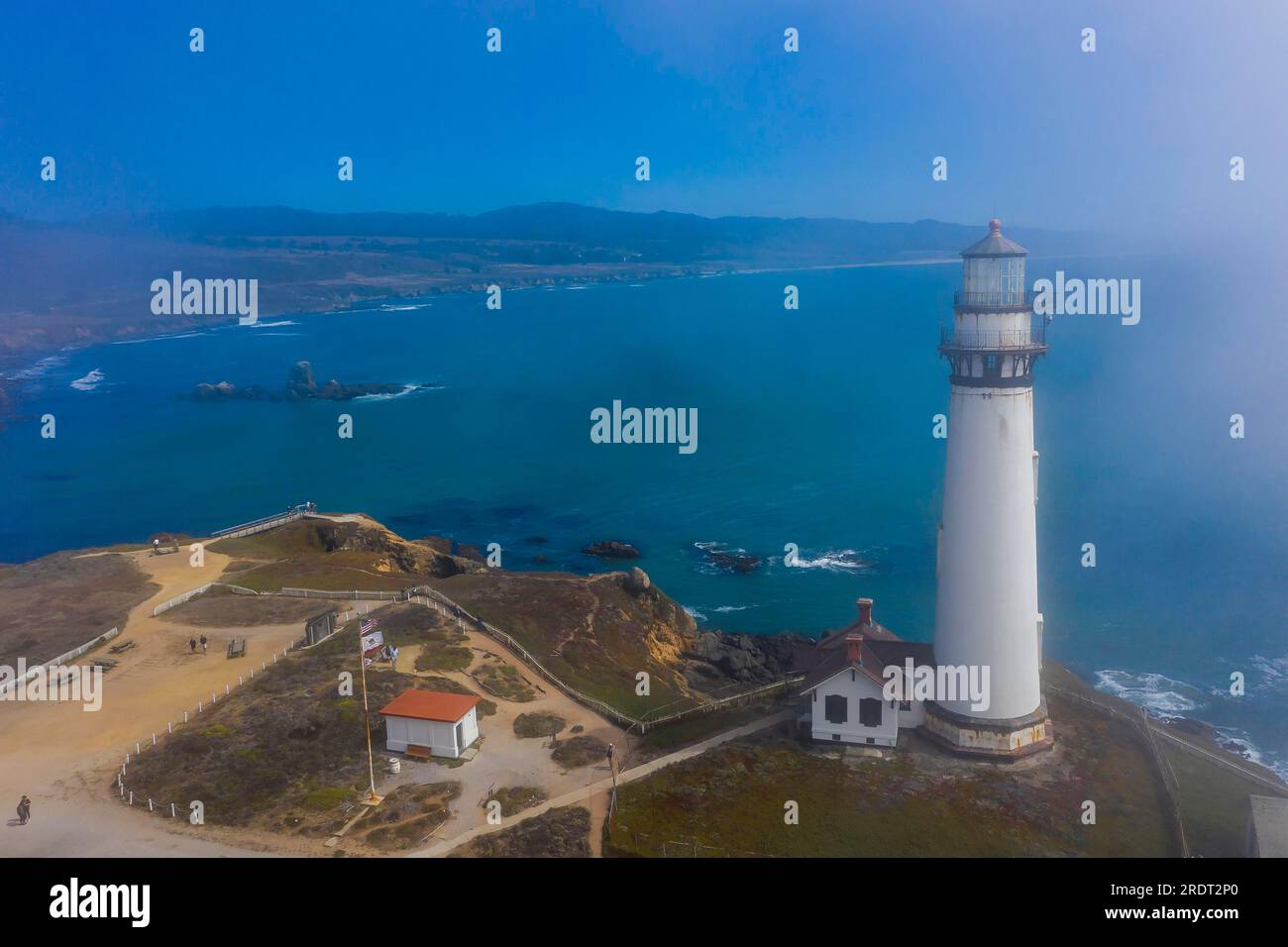 Aerial view of a lighthouse off the California Coast as fog settles in ...