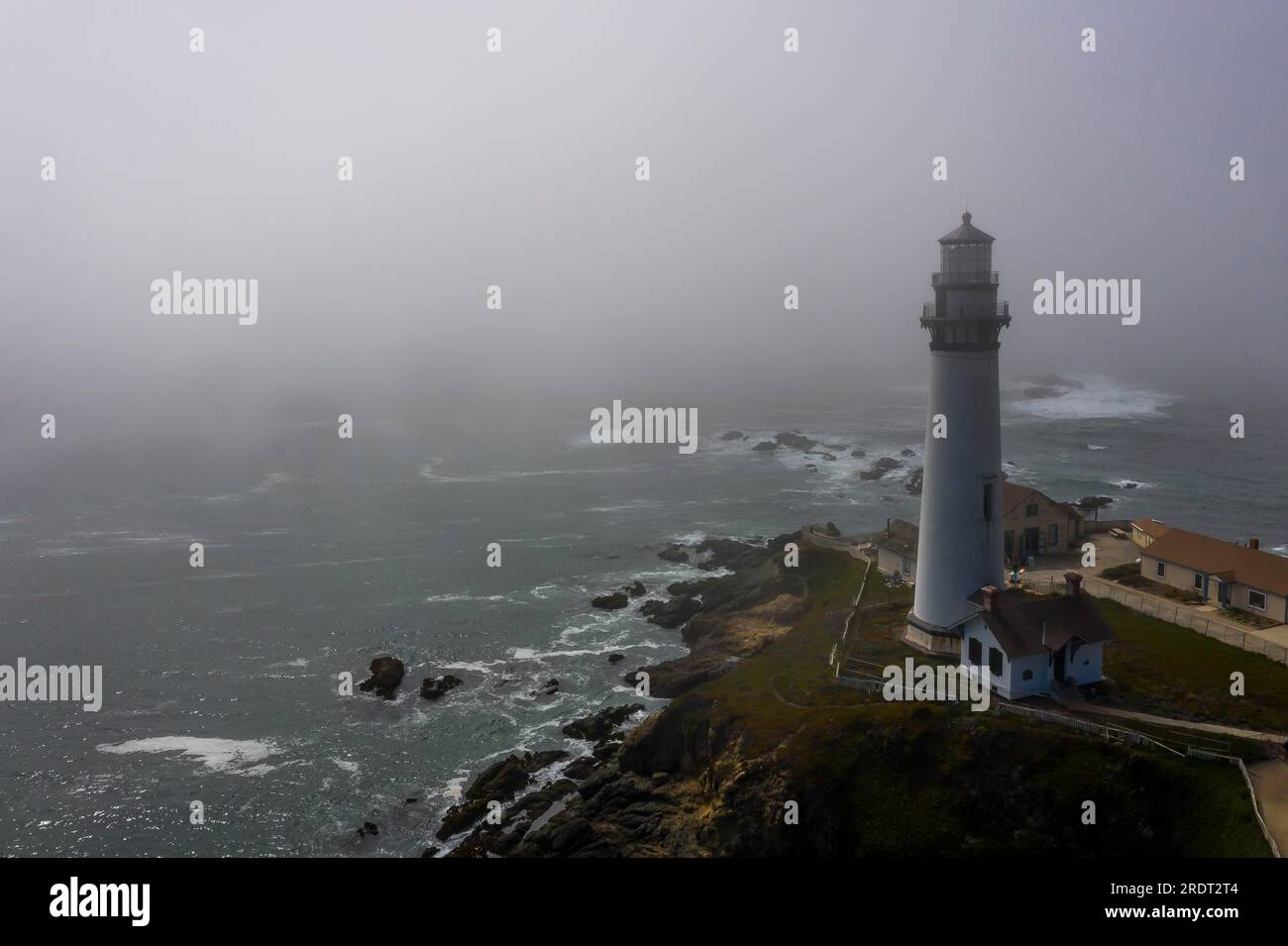Aerial view of a lighthouse off the California Coast as fog settles in ...