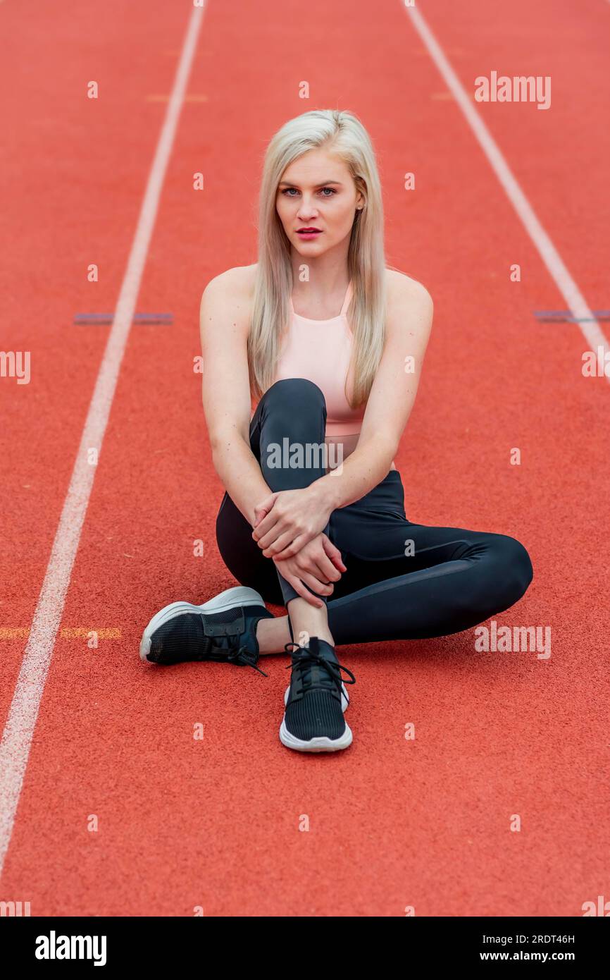 A beautiful young college athlete prepares herself for a track meet at ...
