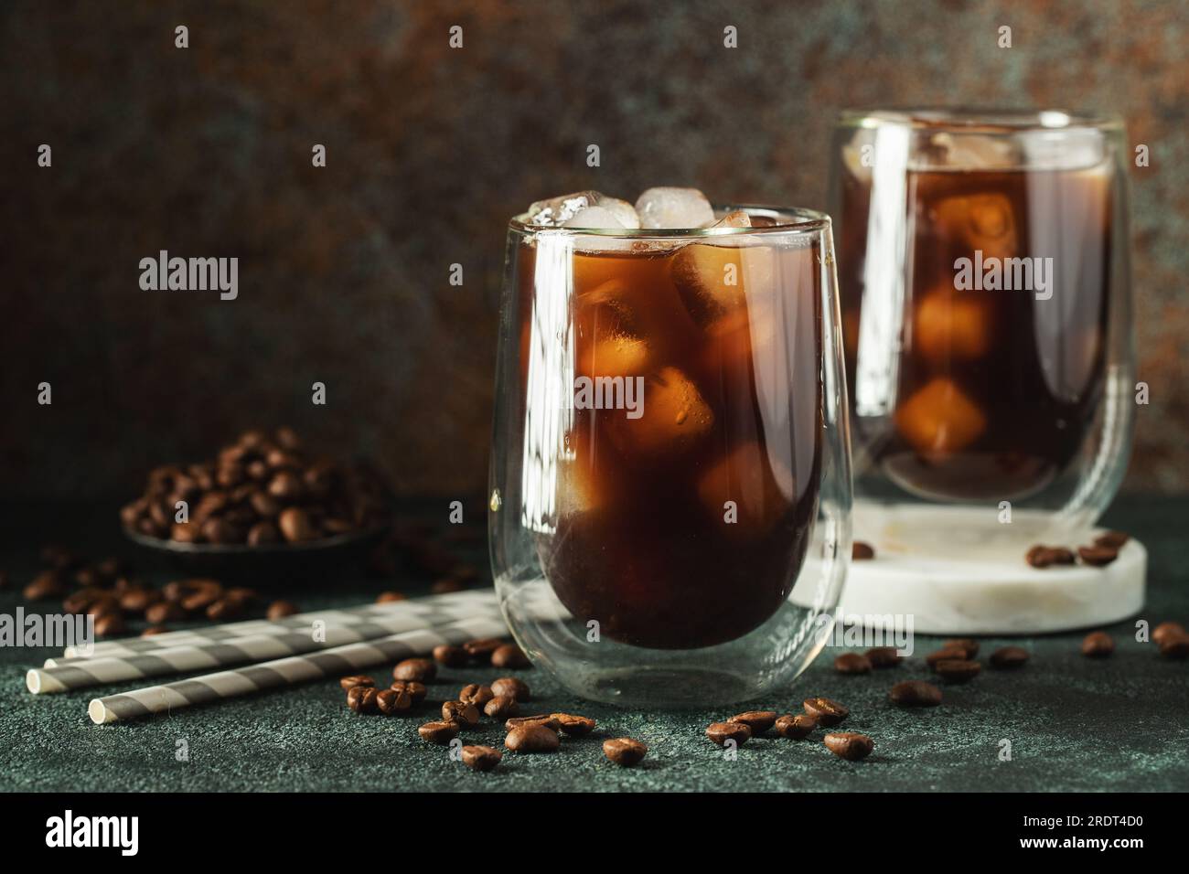 Ice coffee in a tall glass with cream poured over, ice cubes and beans ...