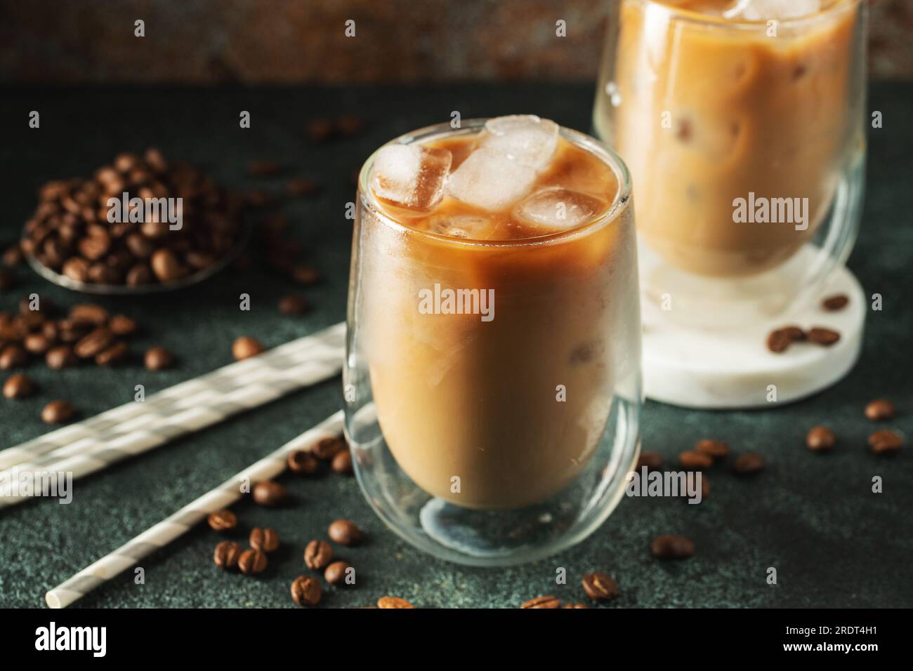 Ice coffee in a tall glass with cream poured over, ice cubes and beans ...