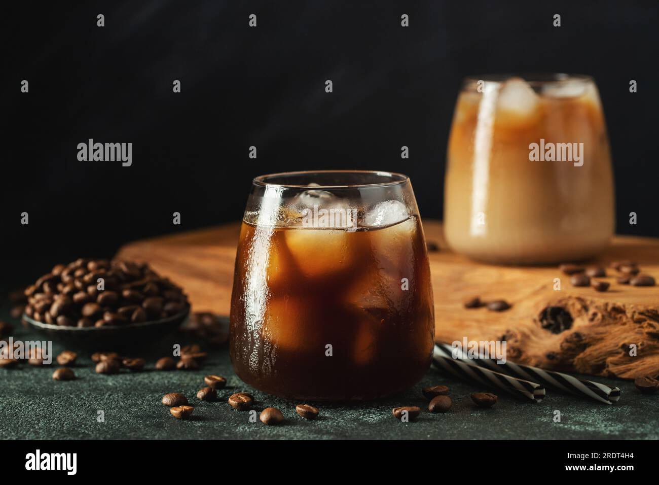 Ice coffee in a tall glass with cream poured over, ice cubes and beans ...
