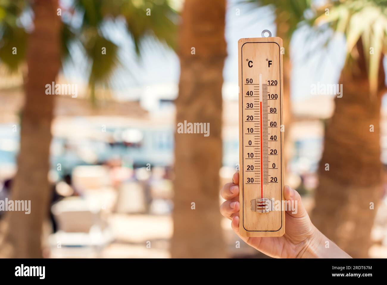 Thermometer in hand on a beach background showing high temperature. Hot ...