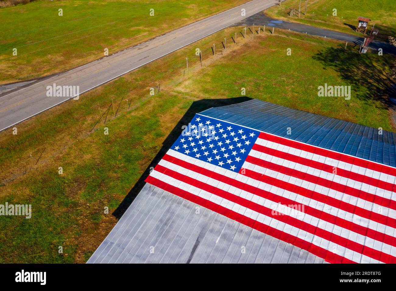 A country road with an American Flag painted on a barn near a farm in ...