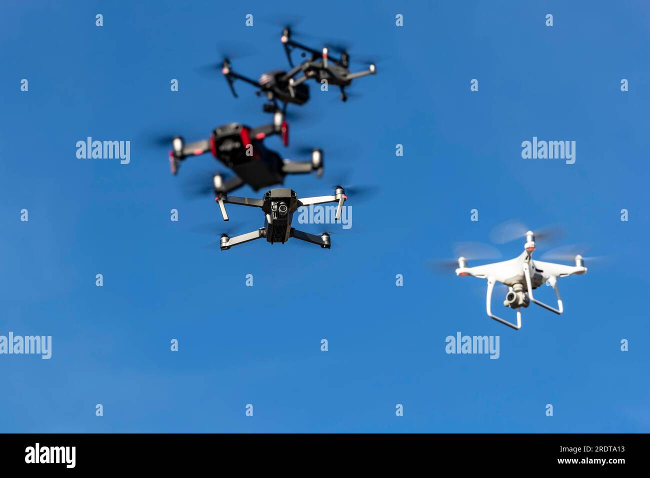 A group of drones fly through the air against a blue sky Stock Photo ...