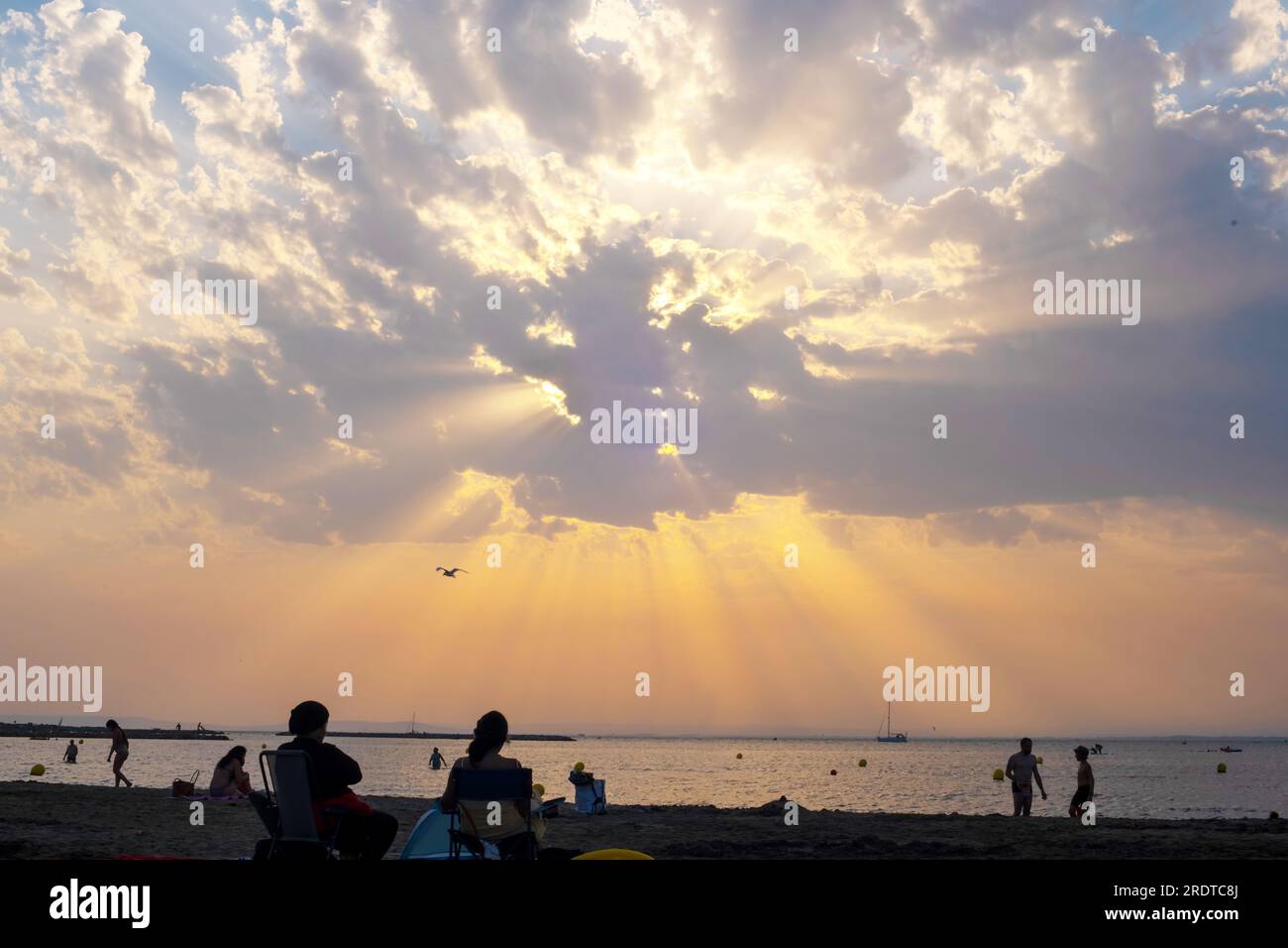 Dramatic sunset sun rays through the clouds on a beach Stock Photo - Alamy
