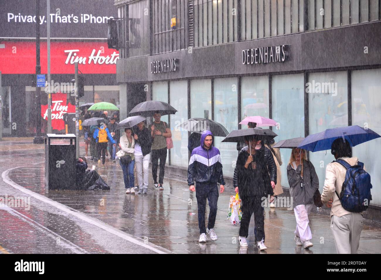 Manchester, UK, 23rd July, 2023. Shoppers battle through torrential ...