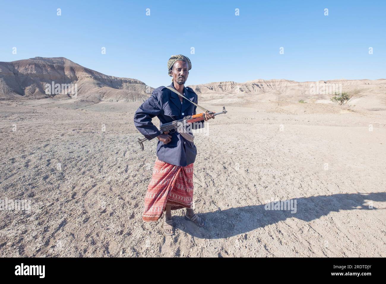 Ethiopian man armed with machine gun standing in the desert. Guard ...