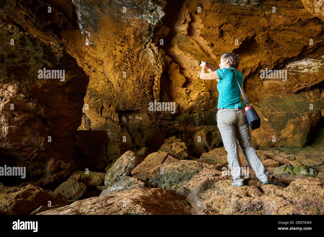 Female hiker photographing the rock formations of Cova Tallada (Montgó ...