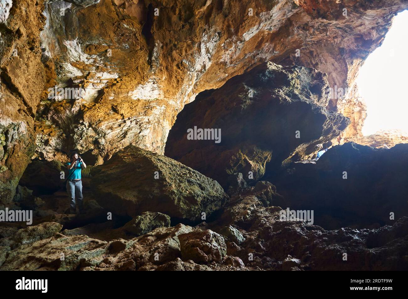 Female hiker photographing the rock formations of Cova Tallada (Montgó ...