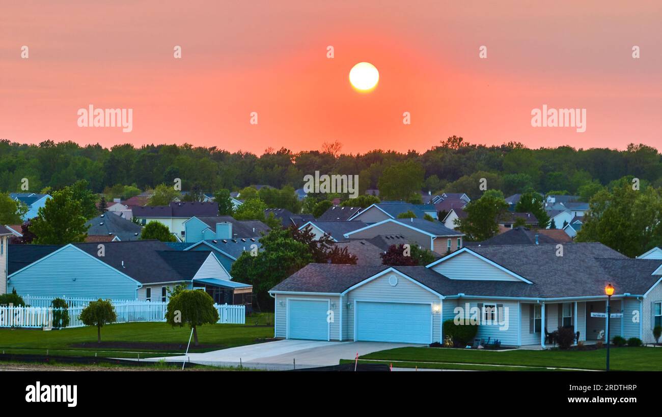 Red, orange sunrise sunset over suburban homes in neighborhood forest ...