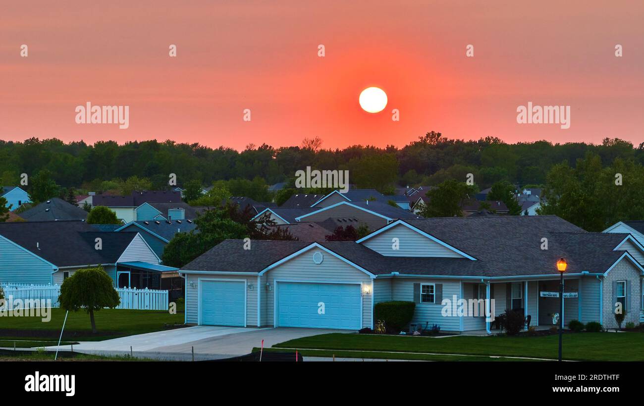 Red-orange sky sunrise sunset over suburban homes in neighborhood ...