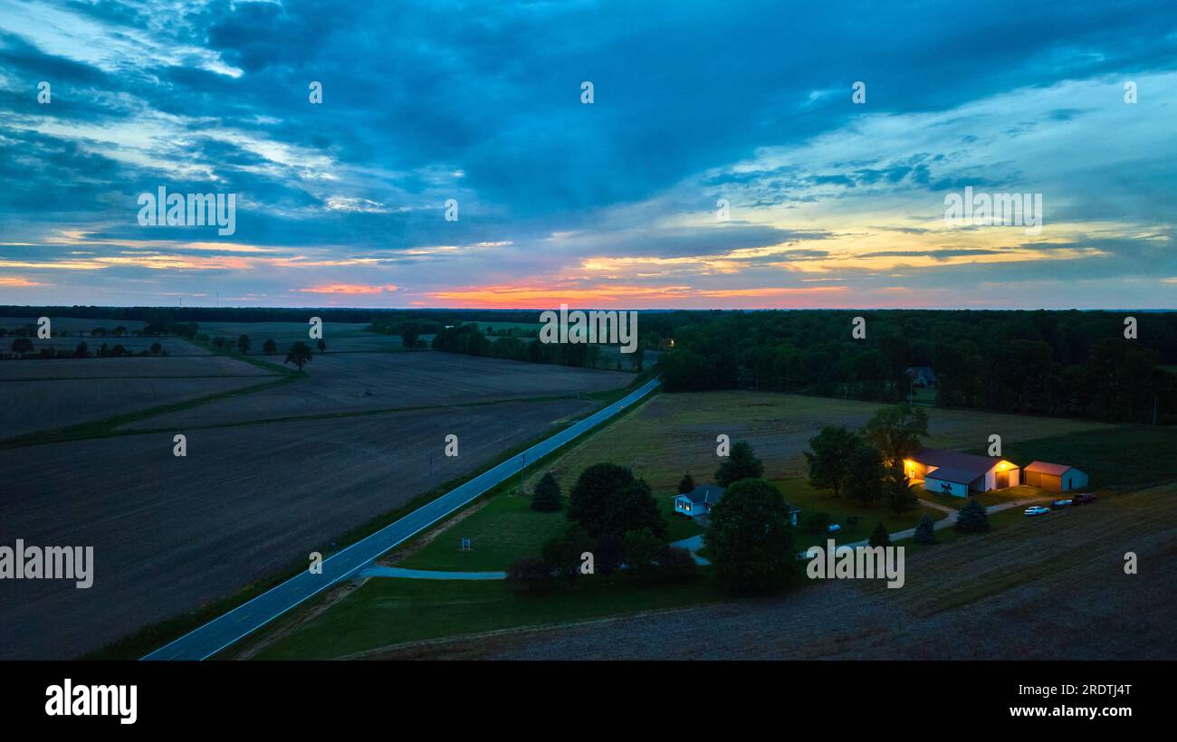Sunset over country farmland with glowing yellow lights on barn Stock ...