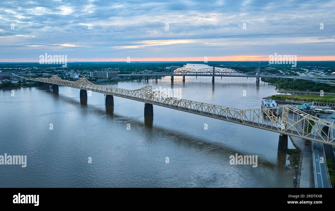 Pink sunset glow on horizon aerial over Ohio River water truss bridges ...