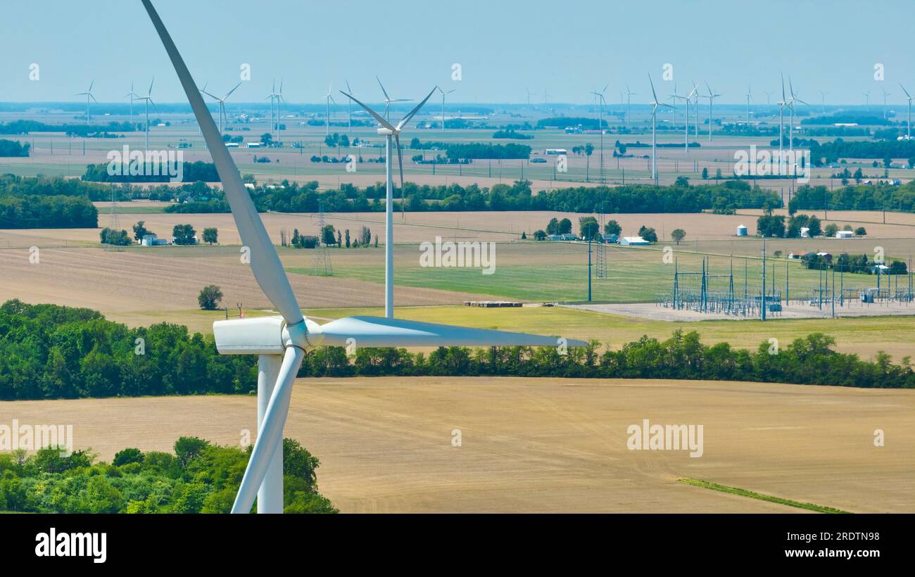 Close up of wind turbine and blades with distant wind farm and ...
