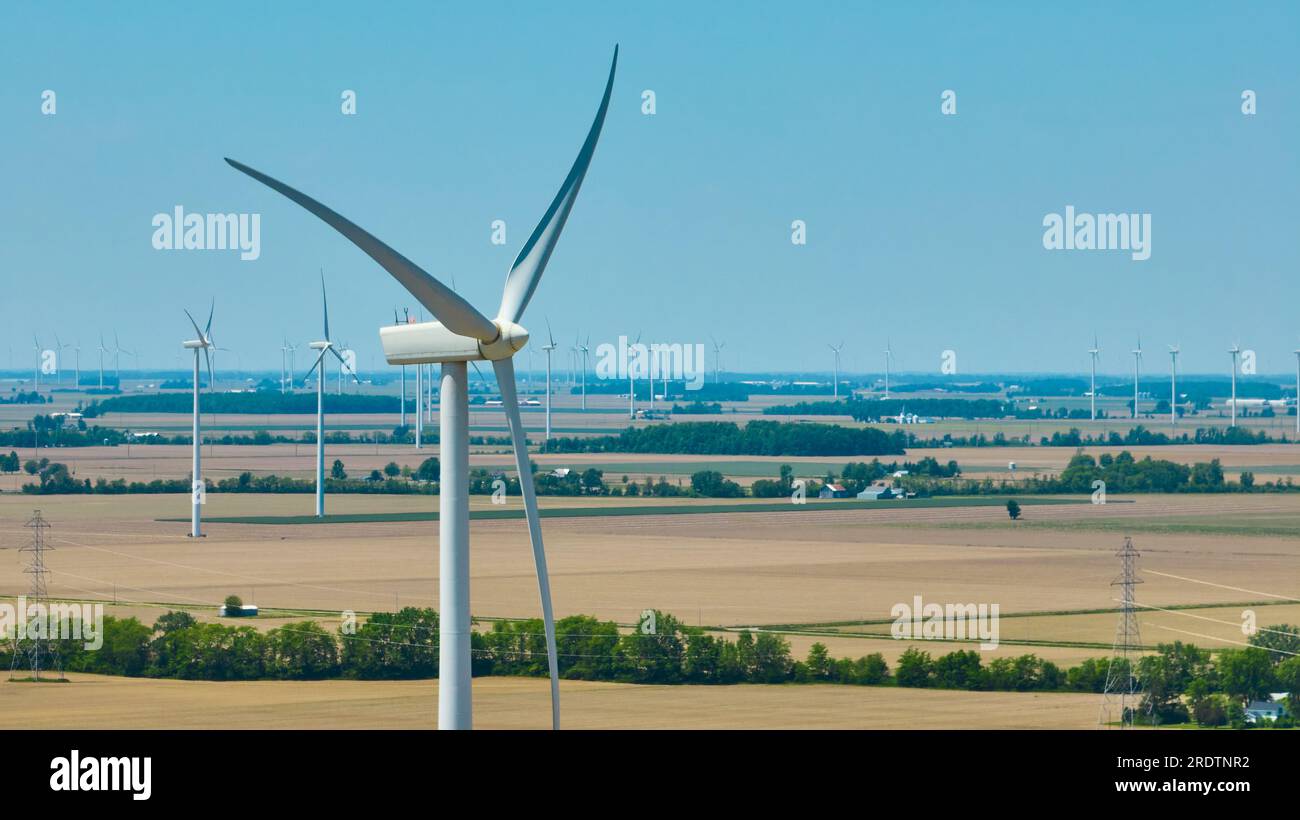Aerial close up of wind turbine propellers with wind farm in background ...