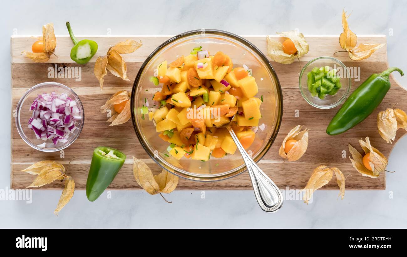 A freshly made golden berry and mango salsa surrounded by ingredients ...