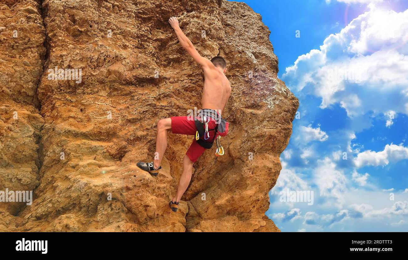Muscular man climbing on rock and blue sky Stock Photo - Alamy