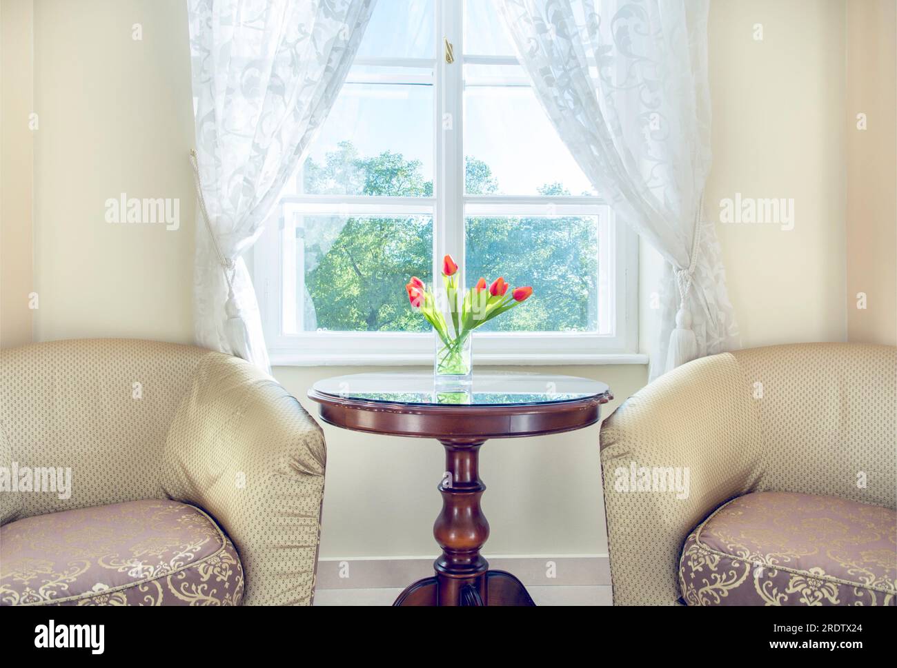 two armchairs and flowers in front of the window Stock Photo - Alamy