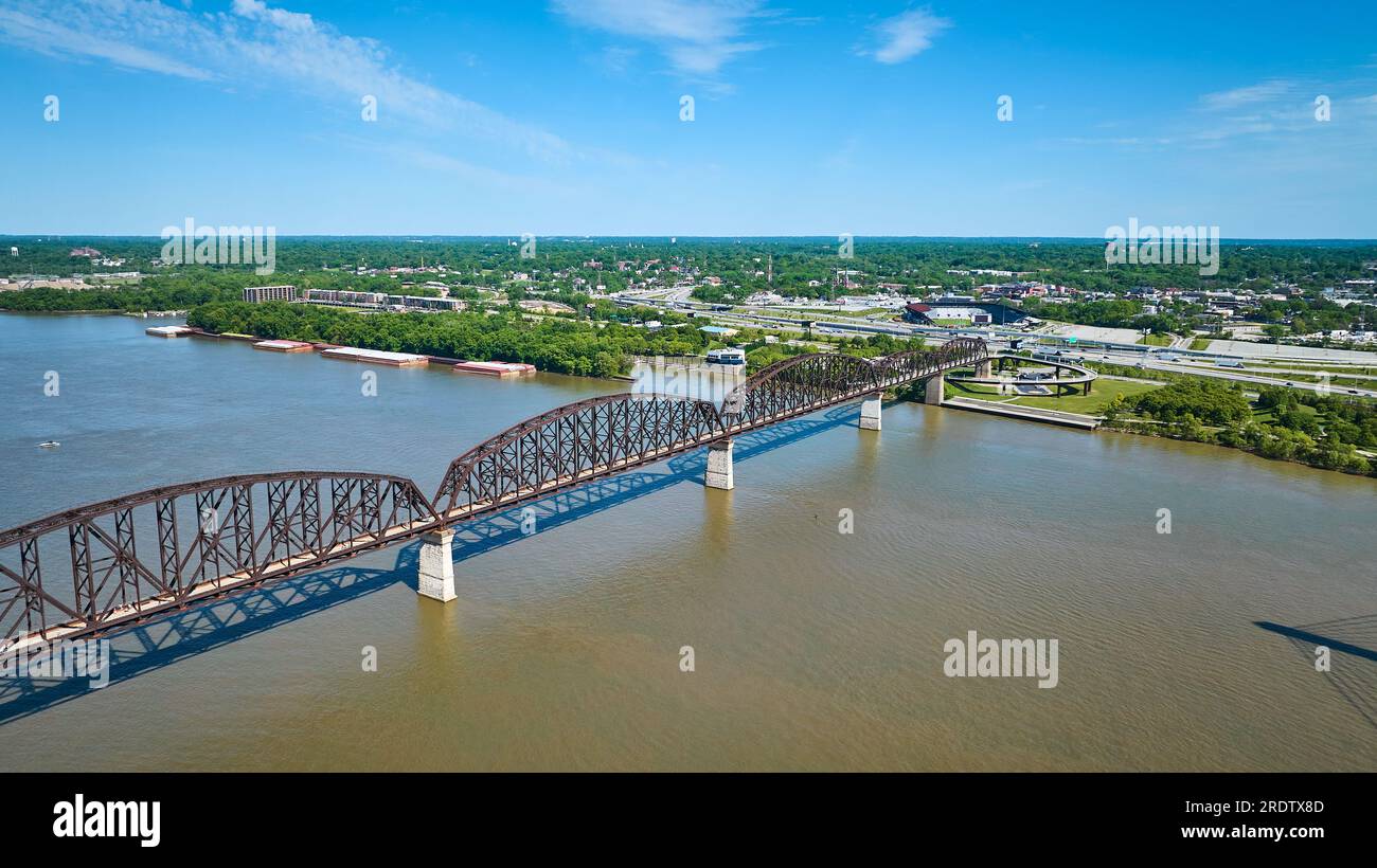 Aerial iron arch bridge over Ohio River water murky distant city blue ...