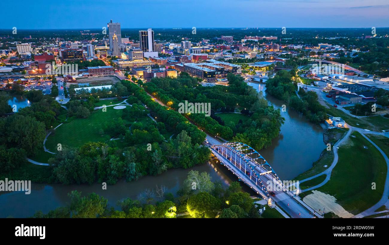 Wide view aerial downtown Fort Wayne at dusk with lights on bridge and ...