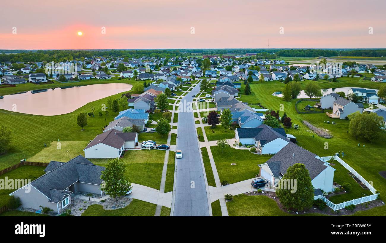 Sunset suburban neighborhood with pond one-story and two-story houses ...