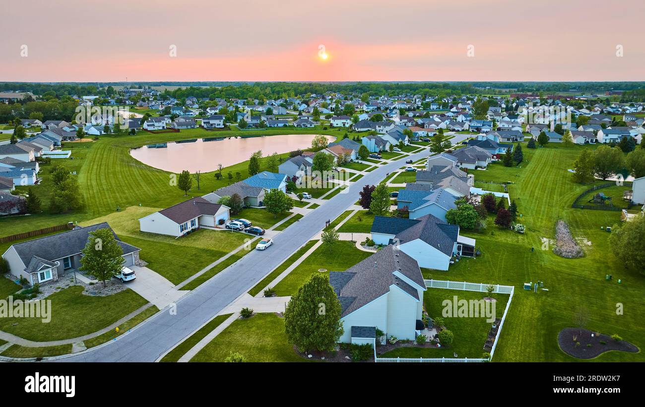 Sunset suburban neighborhood with pond one and two-story houses green ...