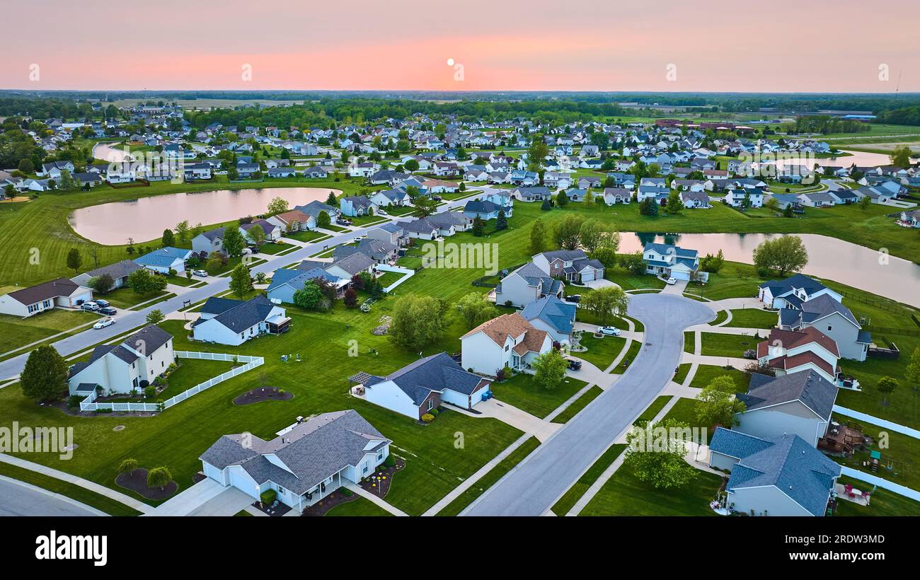 Aerial sunset sunrise over suburban houses neighborhood with four ponds ...