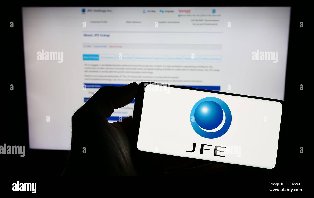 Person holding mobile phone with logo of Japanese steel company JFE Holdings Inc. on screen in ...