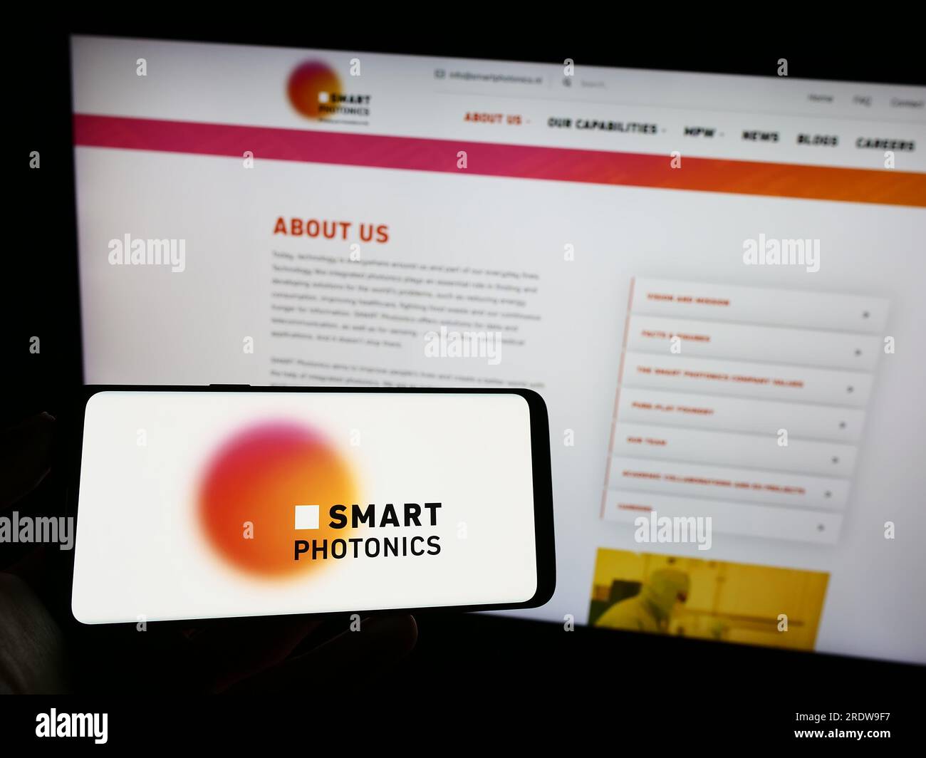 Person holding mobile phone with logo of Dutch semiconductor company SMART Photonics BV on ...