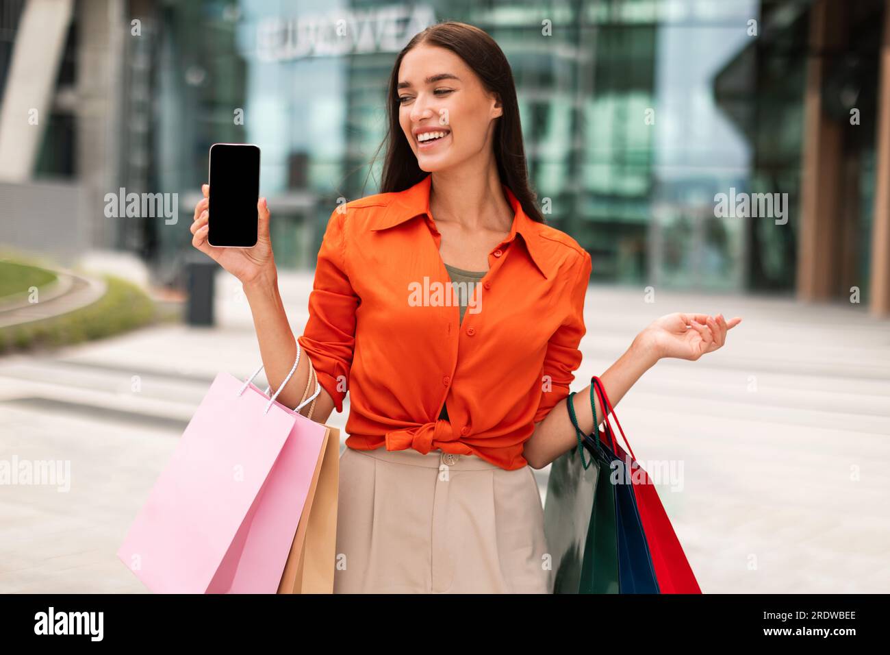 Cheerful Customer Woman Showing Cellphone Blank Screen In Urban Area ...