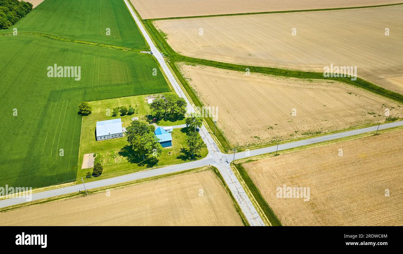 Aerial farm house on corner of intersection with green field and three ...