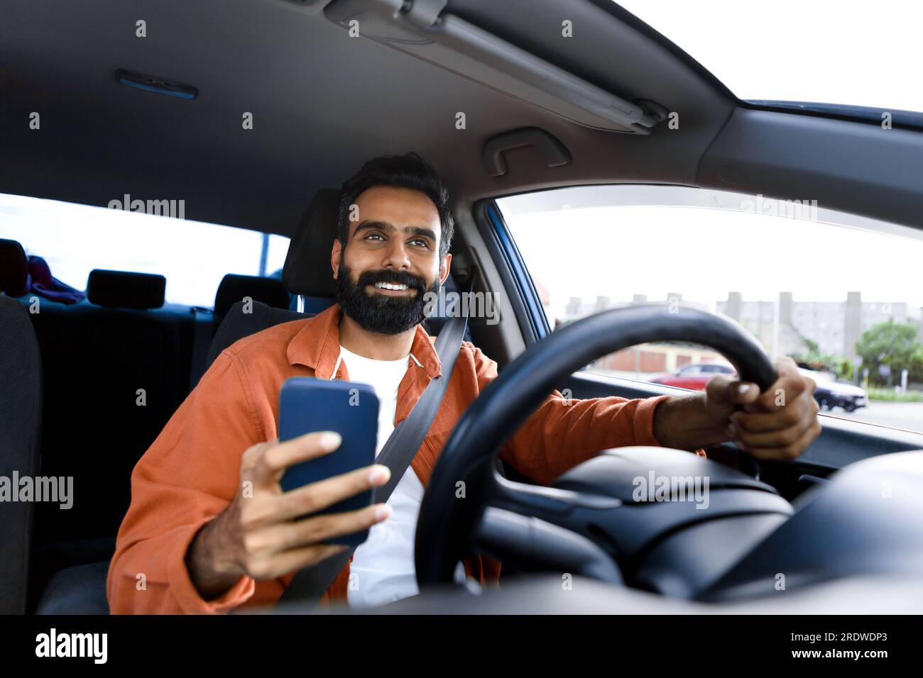 Happy arabic driver man holding smartphone using app in car Stock Photo ...