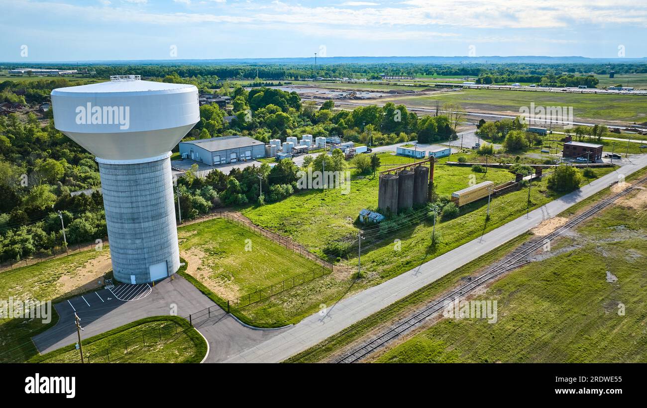 Nondescript white water tower in farmland green fields, train tracks ...