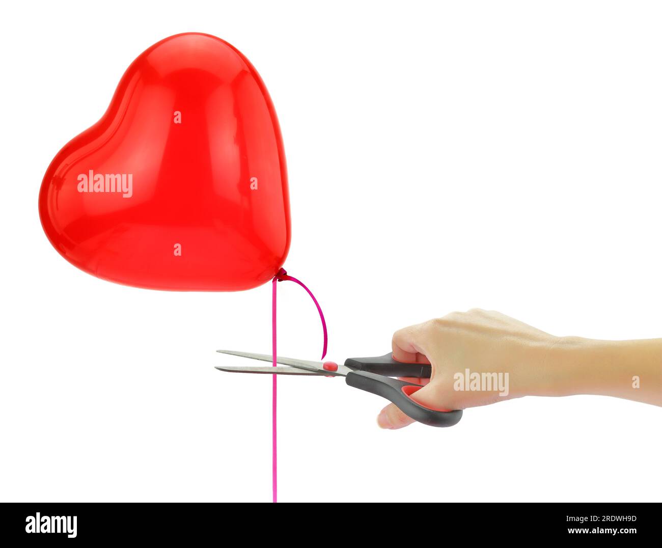 Hand with a scissor cutting a red heart shape balloon ribbon isolated ...
