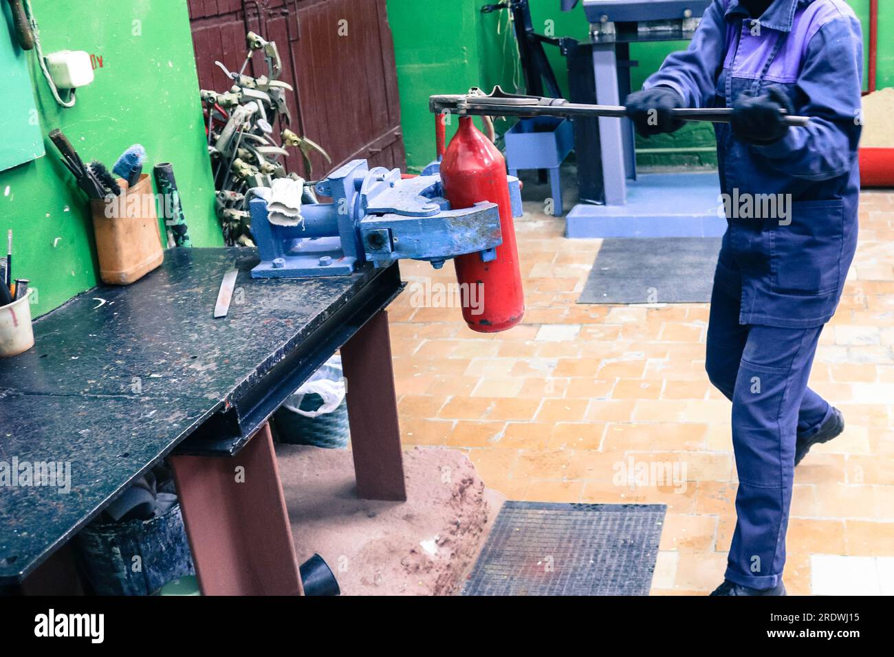 A man working on a large metal industrial vice with a huge gas wrench ...