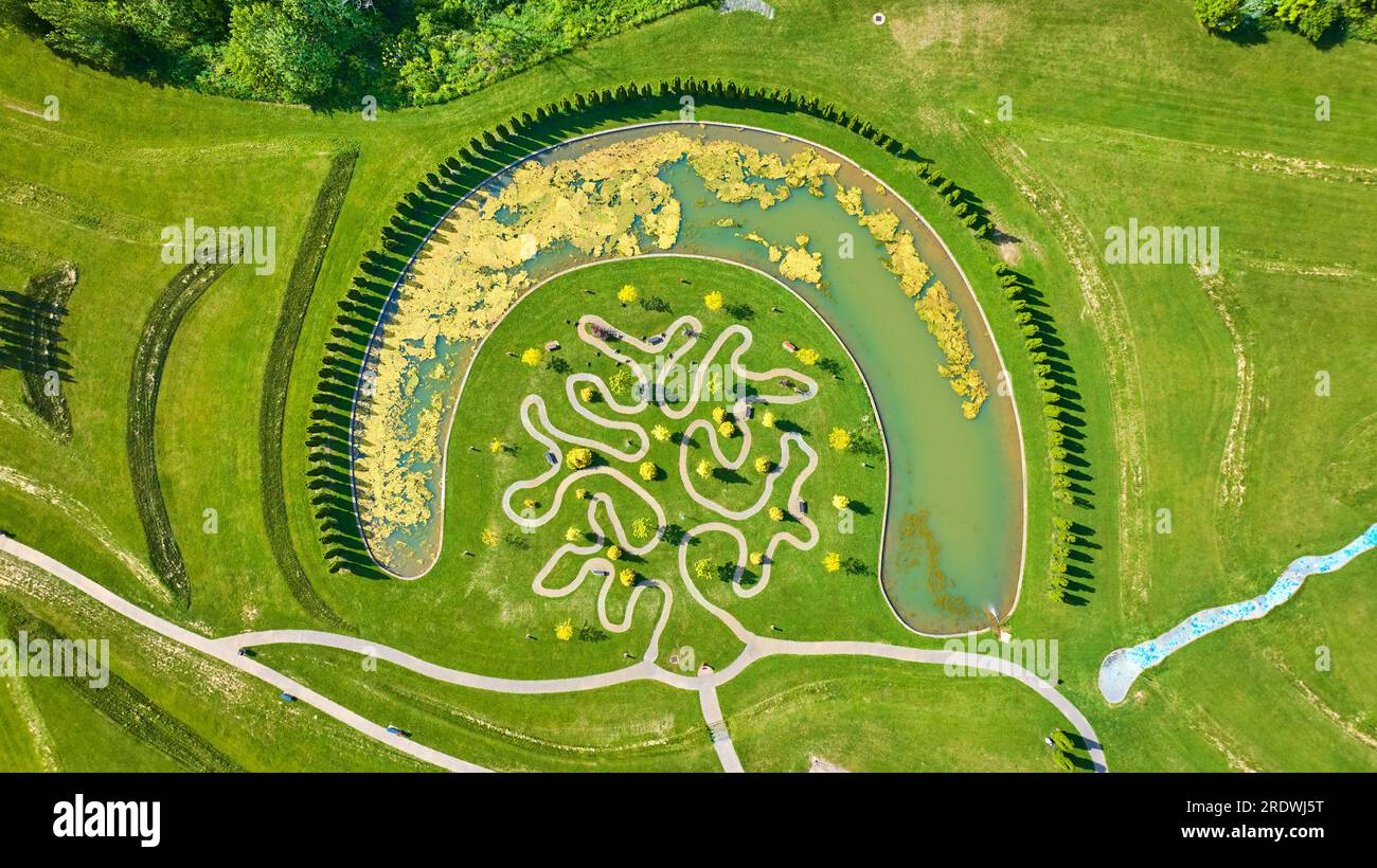 Aerial over tree maze trail in Ariel Foundation Park with curved pond ...