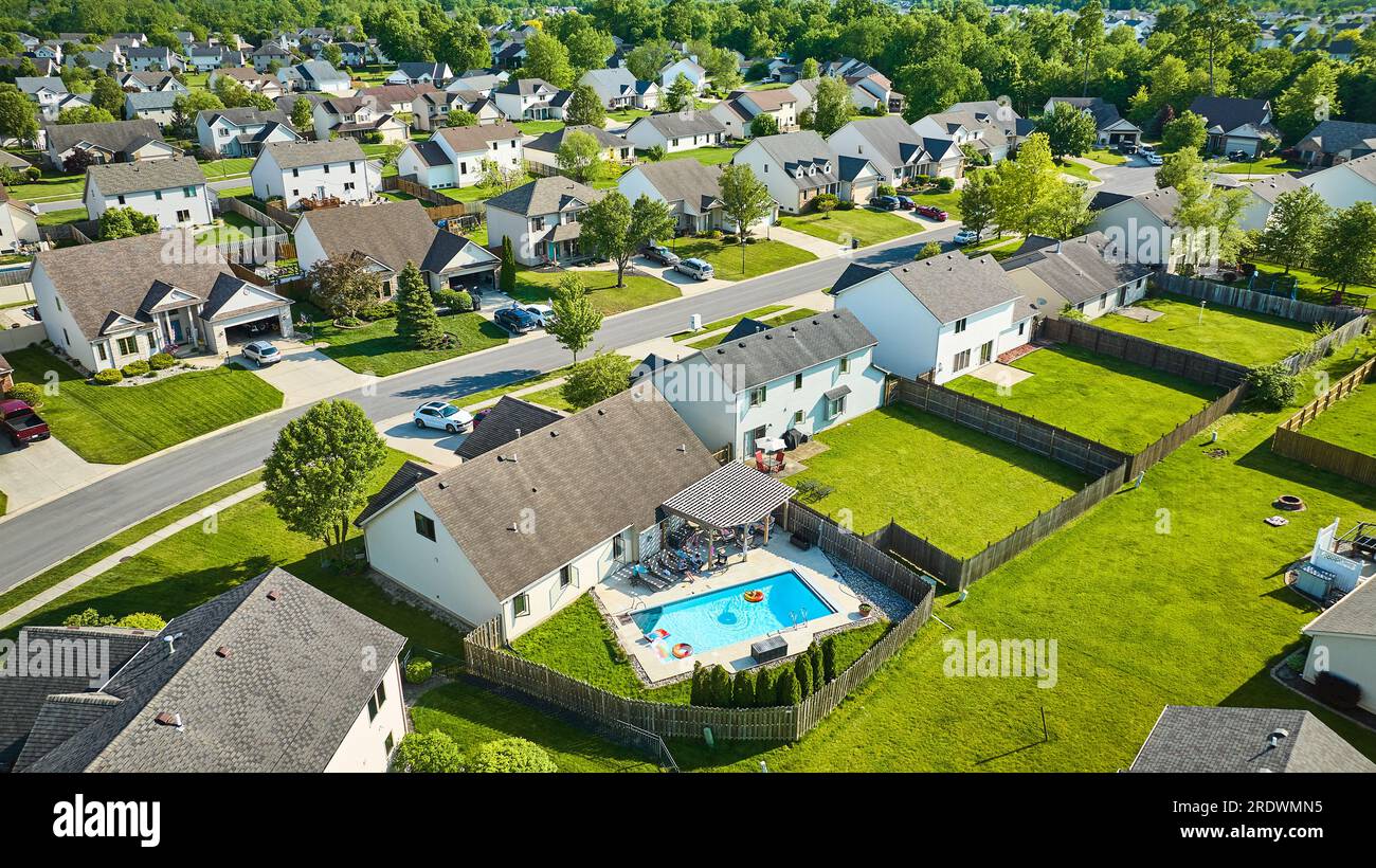 Summertime aerial of pool behind house in neighborhood with floaties ...