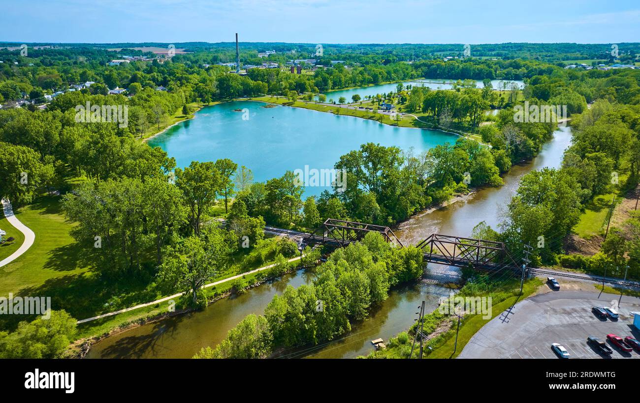 Dazzling turquoise blue pond with lush summertime trees and train ...