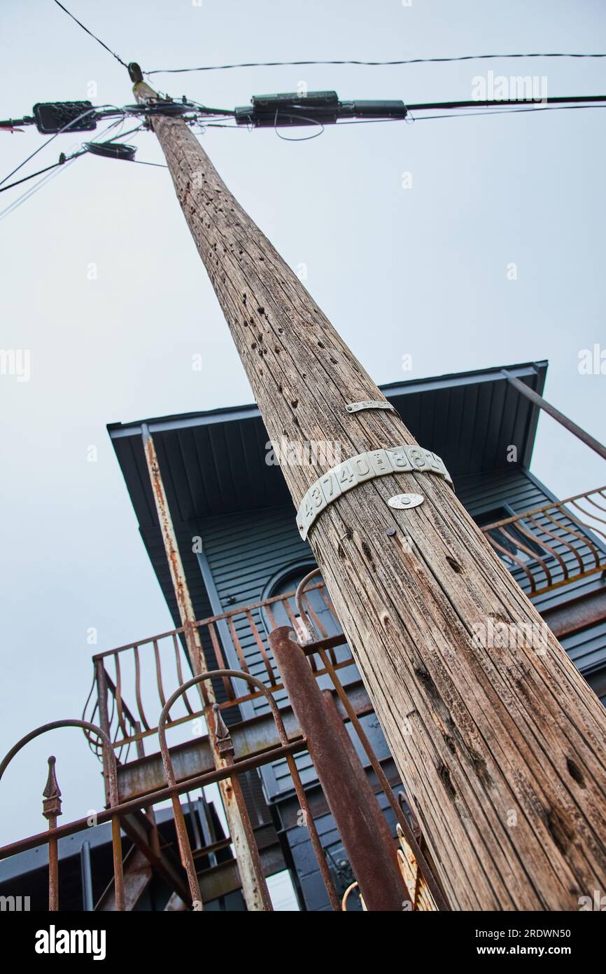 Tall telephone pole bottom up view with rusty metal railing on blue ...