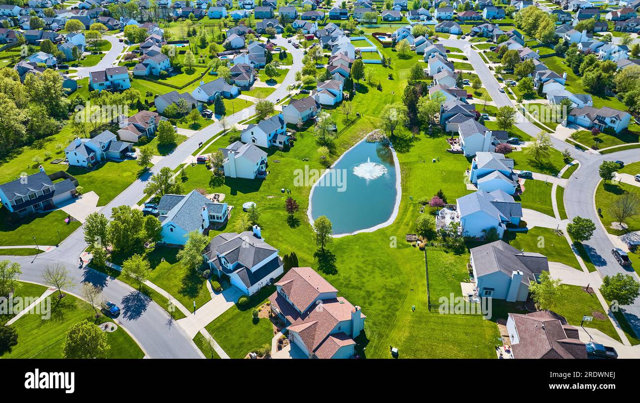 Water fountain in blue pond in large suburban neighborhood full of ...