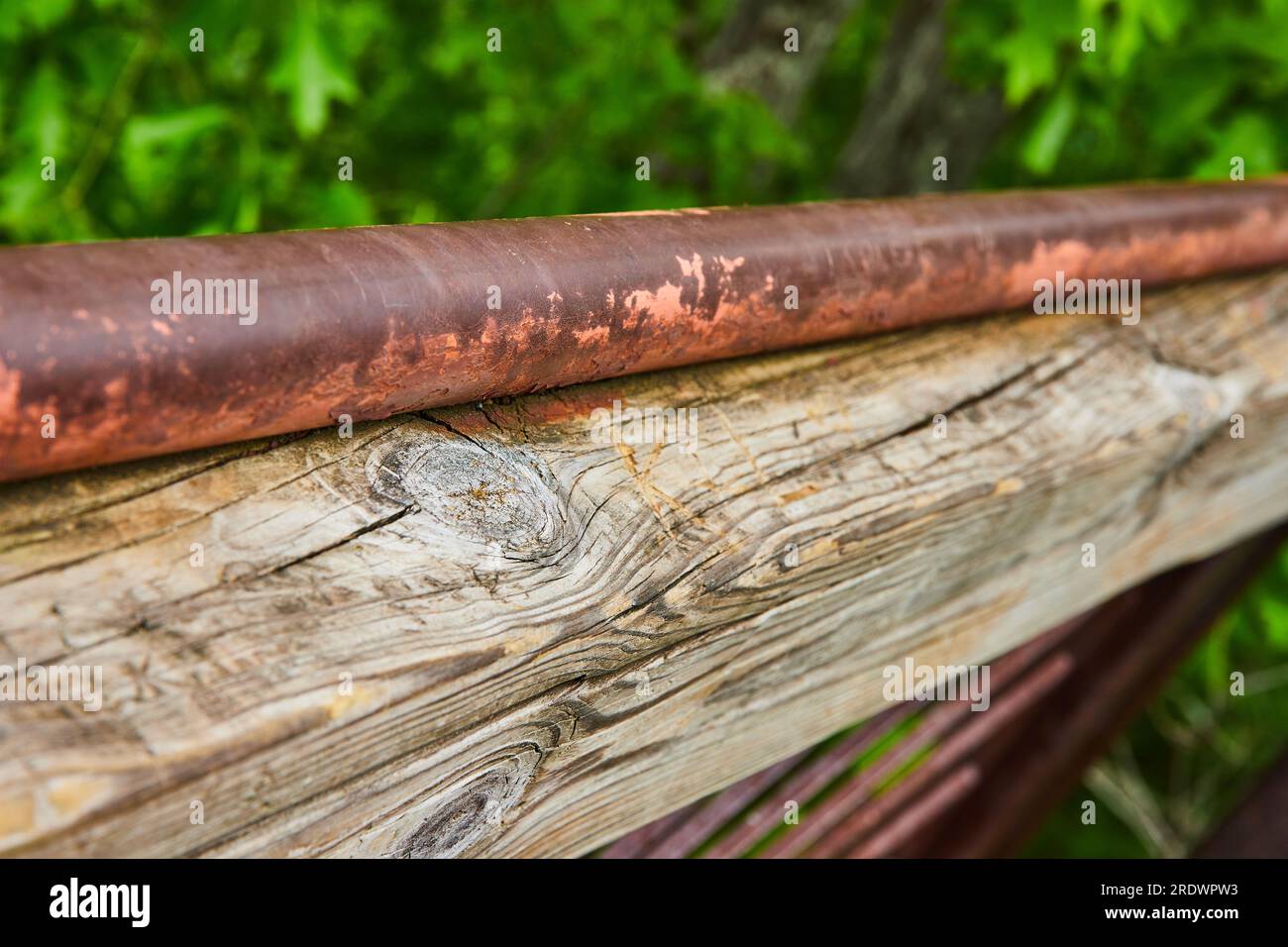 Fading and chipped red paint on metal pole resting on carved wood beam ...
