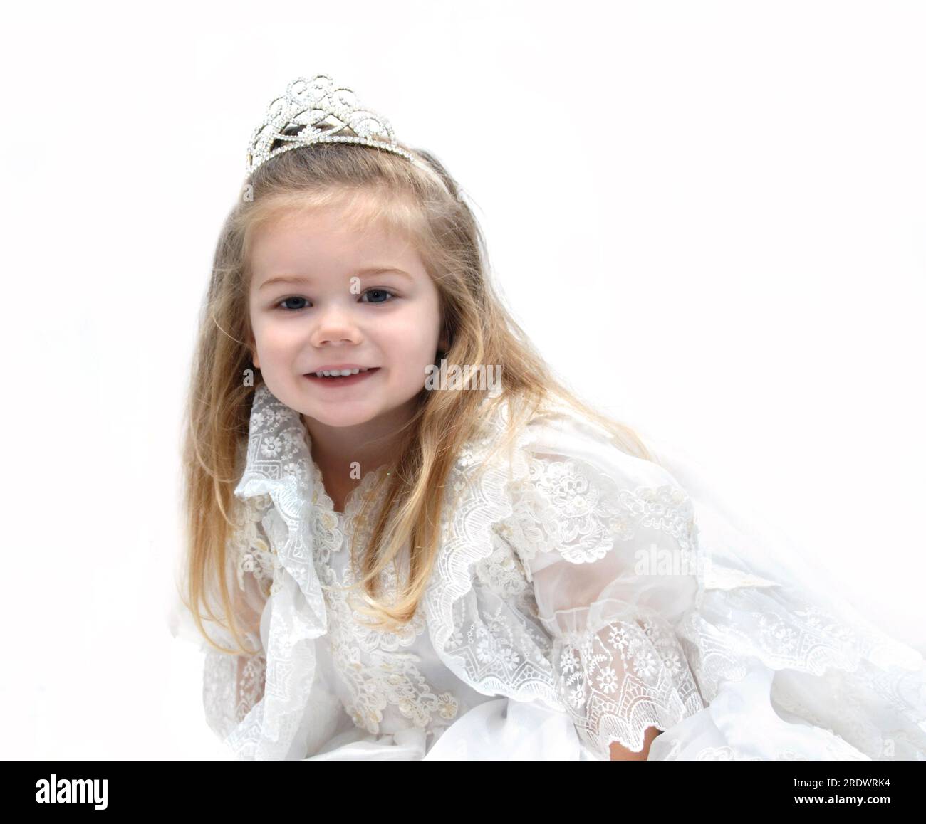 Little girl wears an elegant wedding dress and crown. She is sitting in ...
